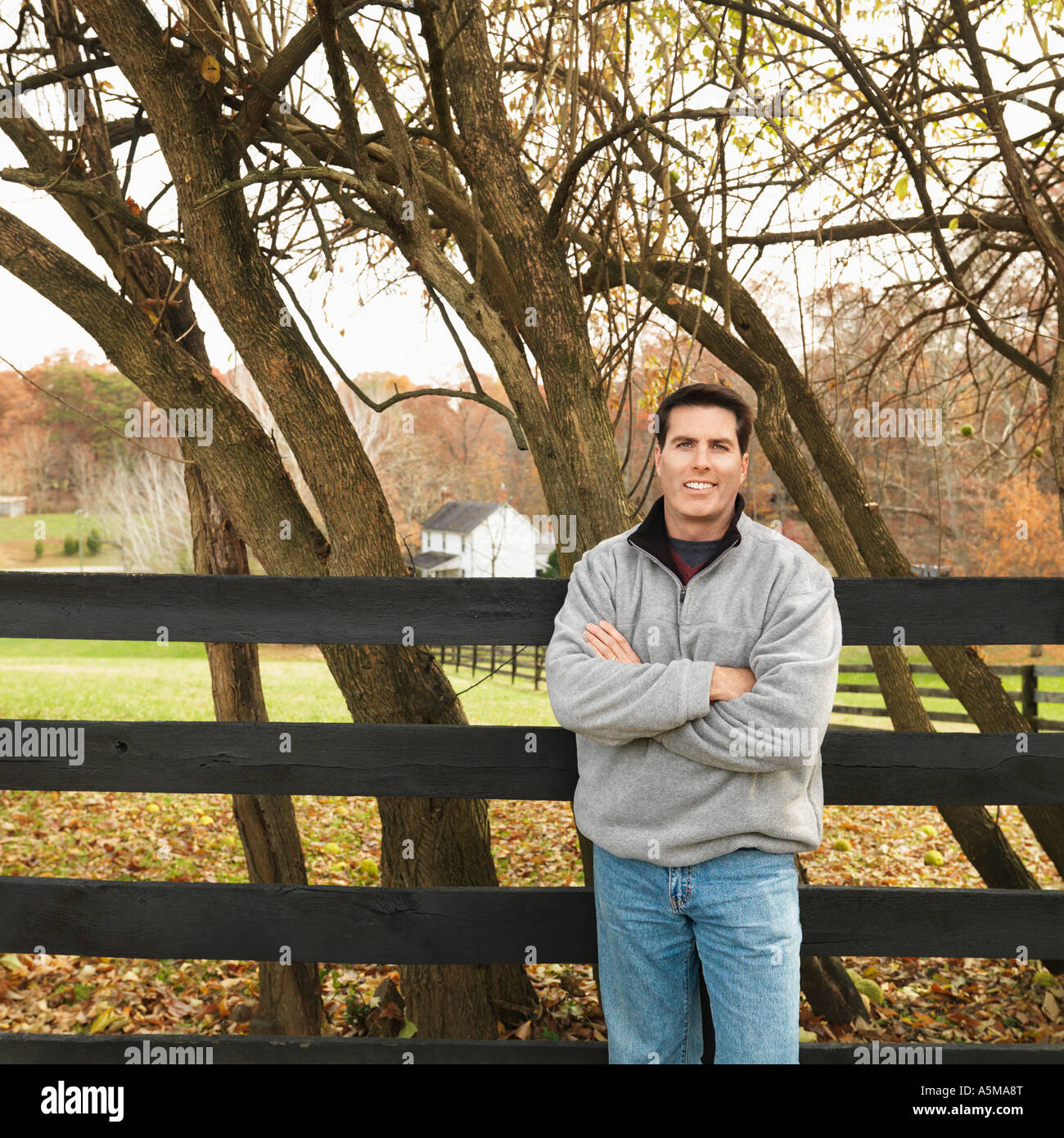 Caucasian man leaning against fence smiling in rural setting Stock ...