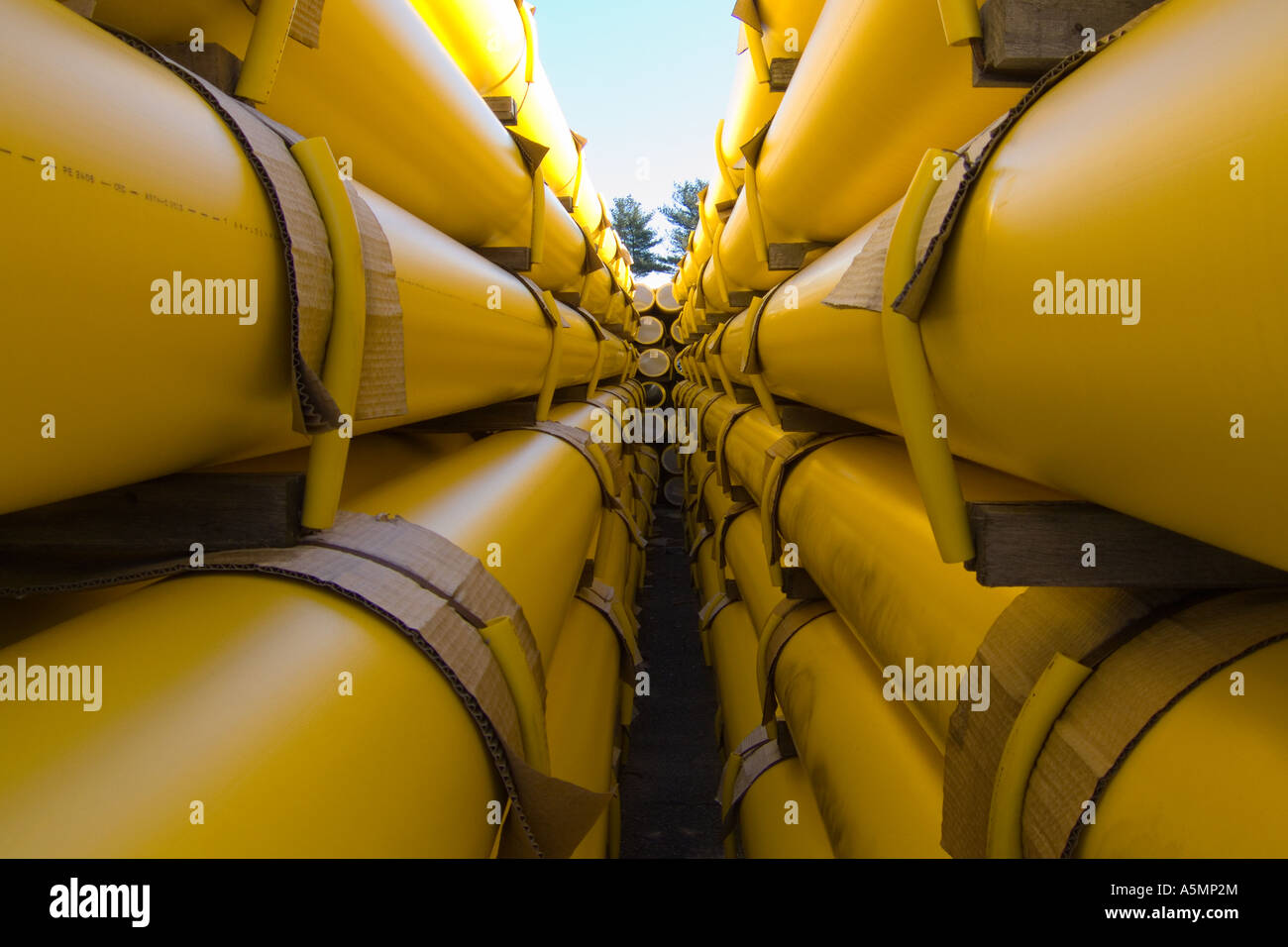 a stack of yellow natural gas utility pipes in a utility company yard ...
