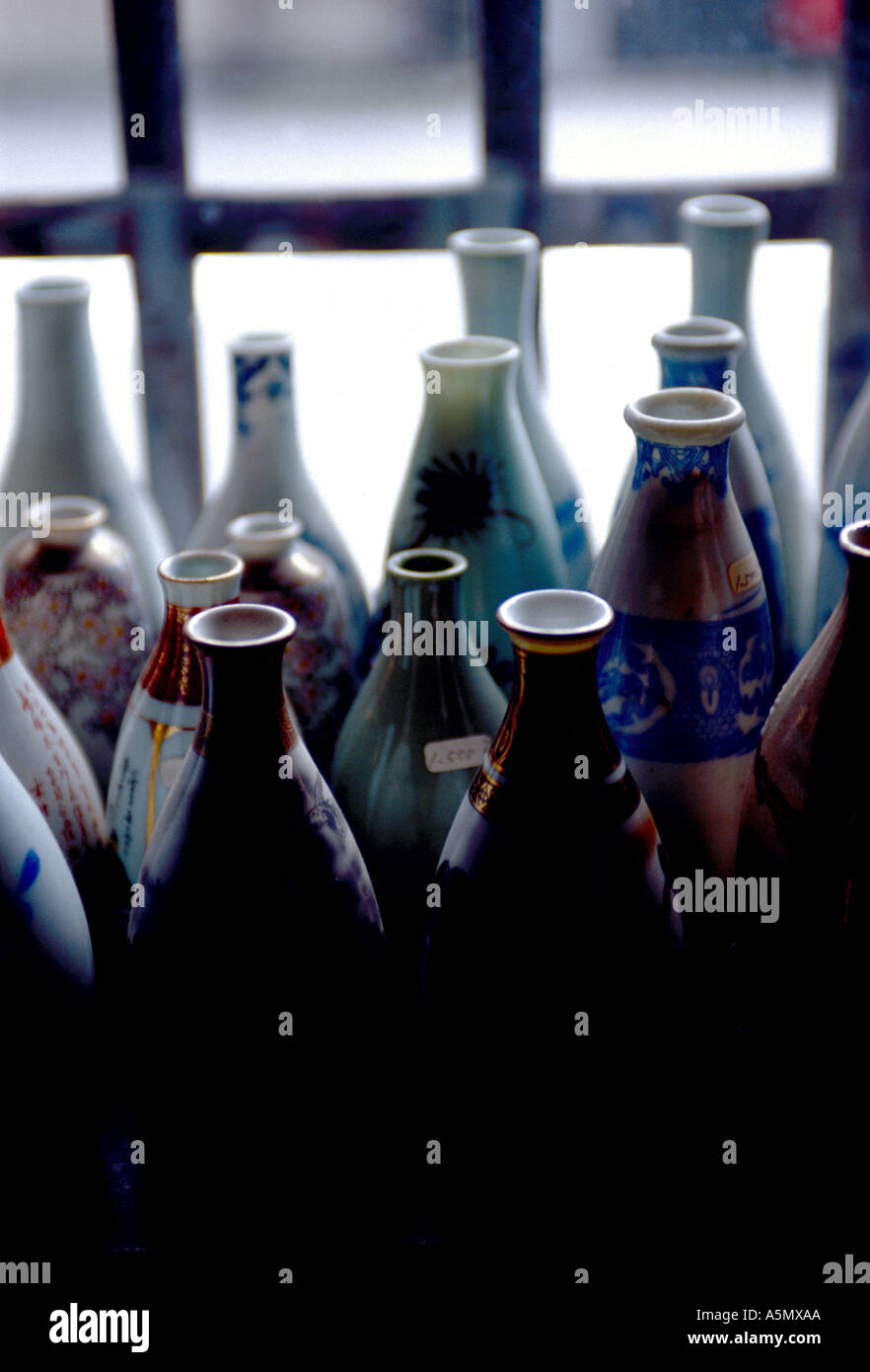 Old sake bottles on display in a window inside an antique shop in ...