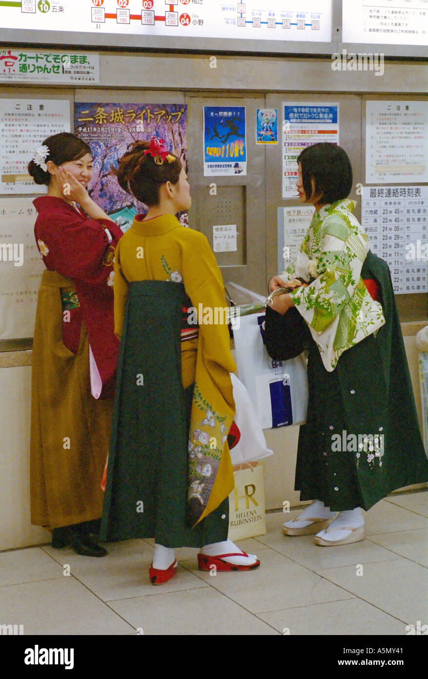 Three young Japanese women gossip in front of a train ticket machine in ...