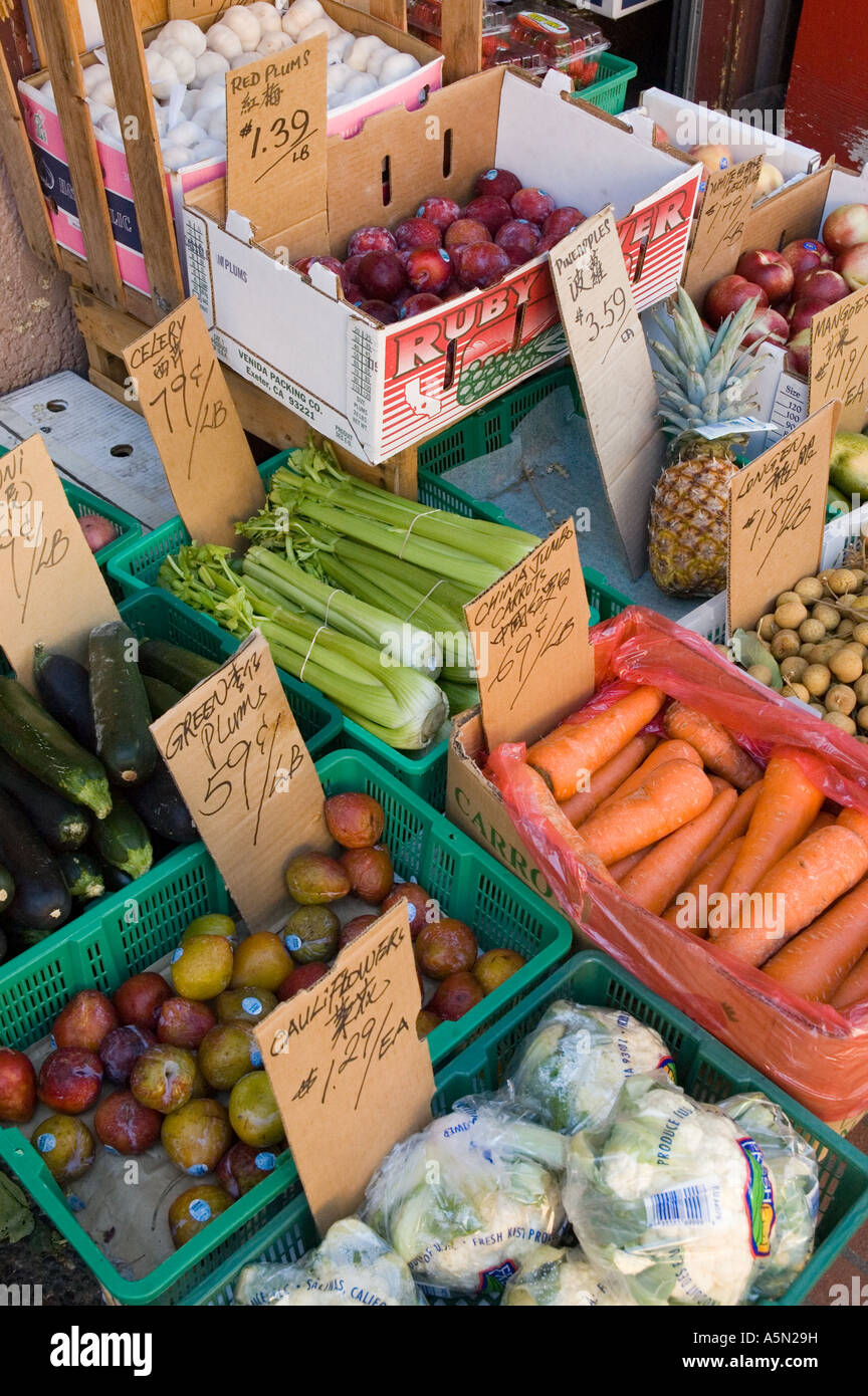 fruit and vegetables displayed in bins on the sidewalk outside a store ...