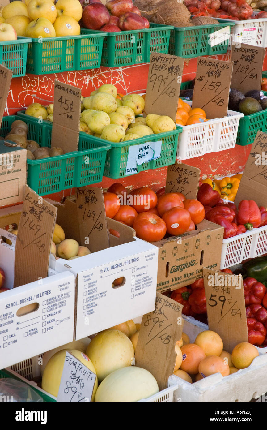 fruit and vegetables displayed in bins on the sidewalk outside a store ...