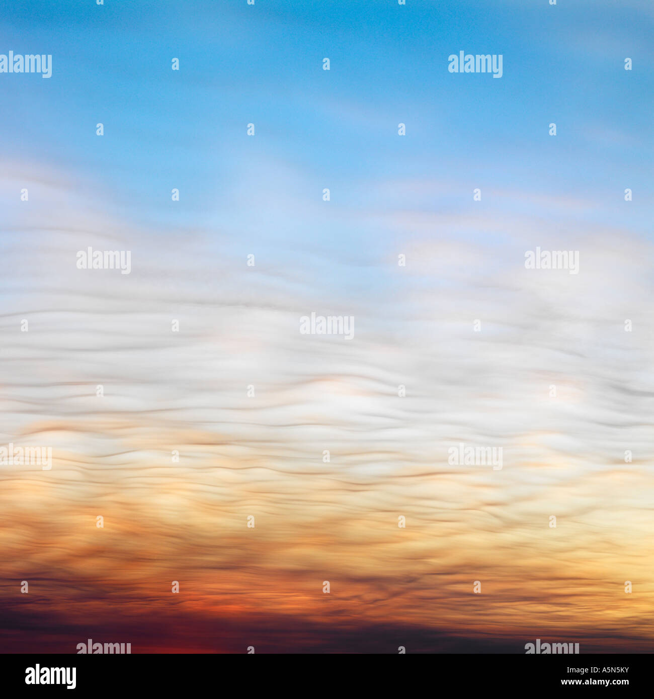 Wispy clouds in sunset colored sky Stock Photo - Alamy