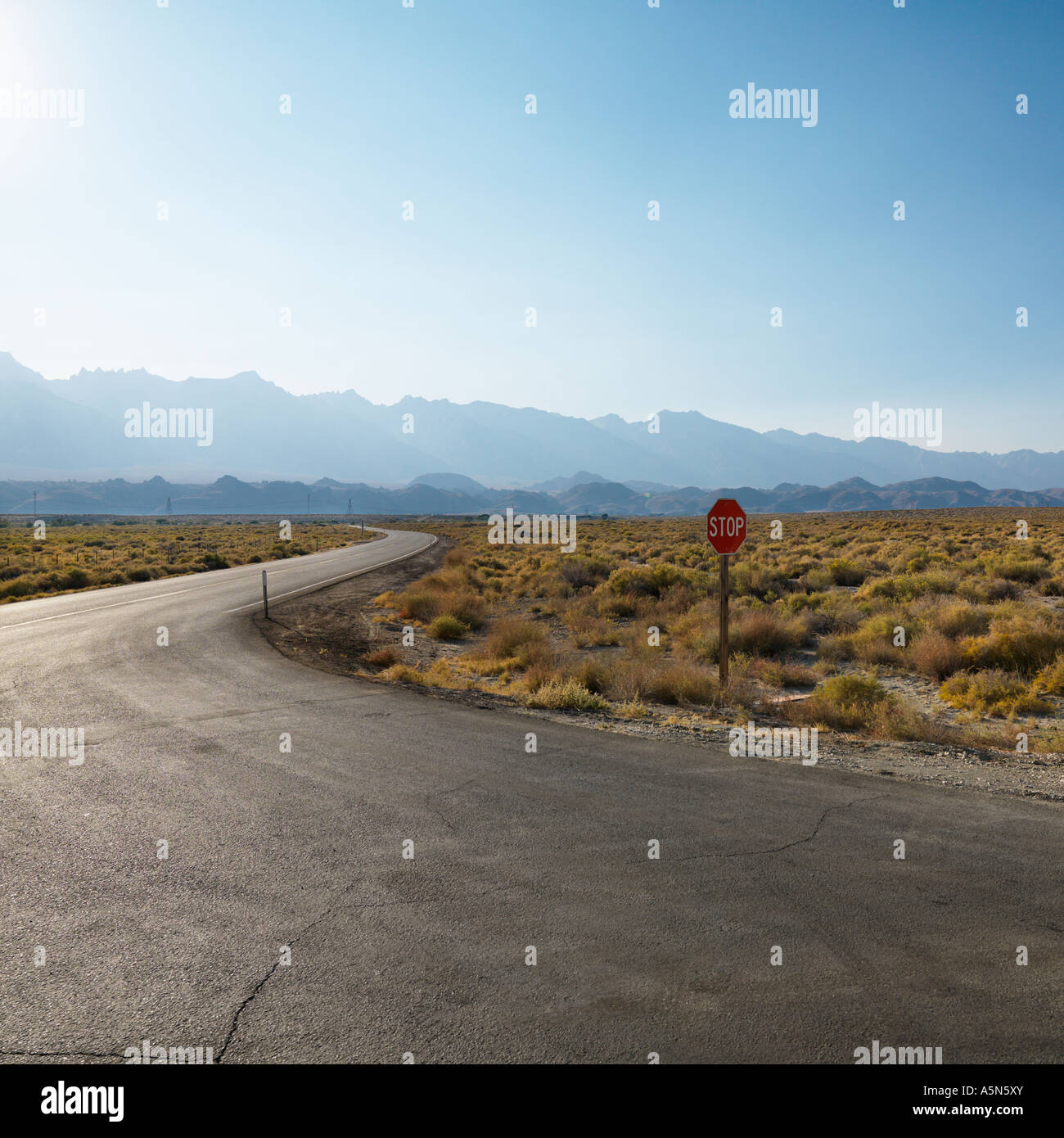 Road with stop sign in barren landscape with mountain in distance Stock ...