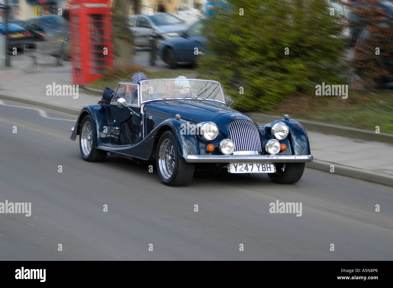Blue morgan sports car travelling through the rural Cotwold town of ...