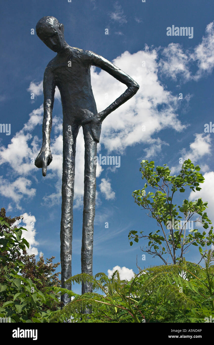 Pointing Finger: A large tall bronze figure statue points down along ...