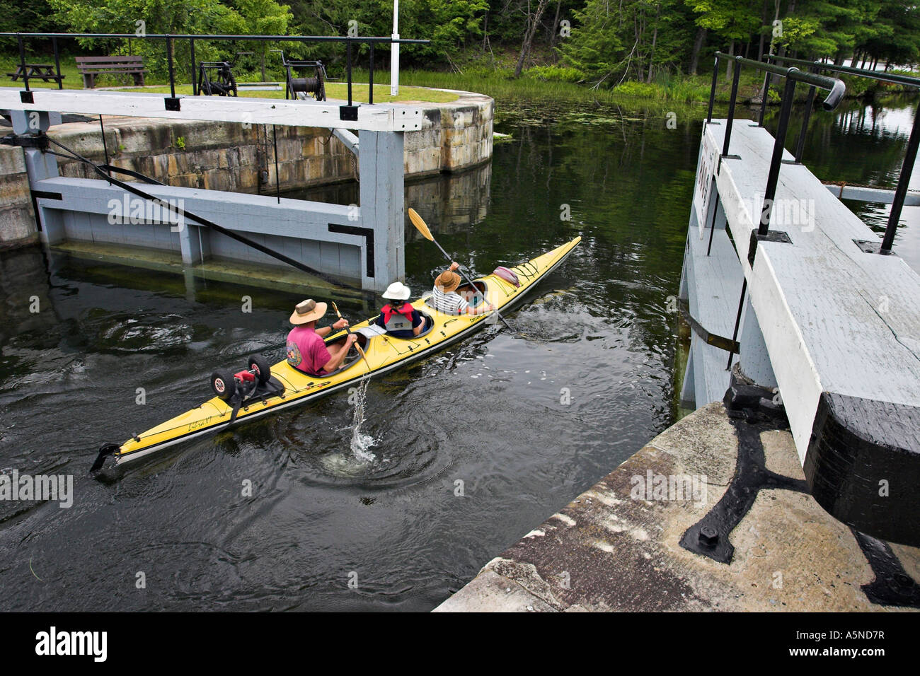 Through the Lock: A long yellow kayak with a father and two sons aboard ...