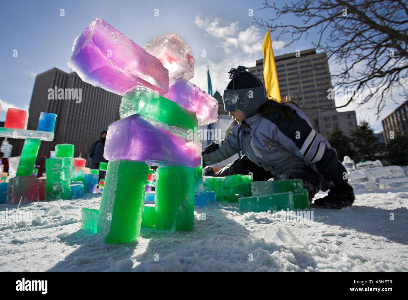 Larger than Life: a child plays in the snow with coloured blocks of ice ...