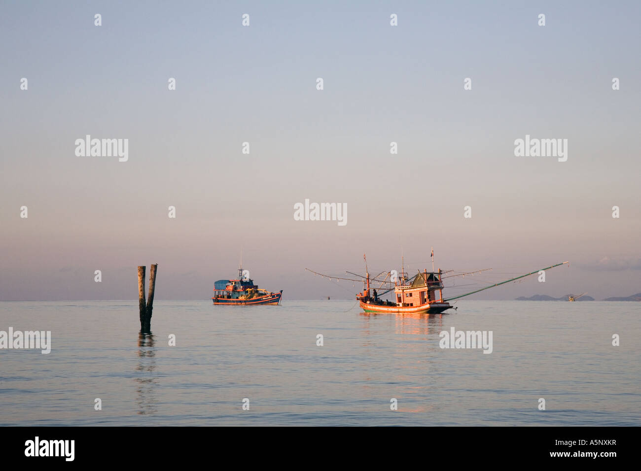 Traditional Thai Fishing Boats at Dawn light or sunrise The Andaman Sea Krabi Beach resort ...