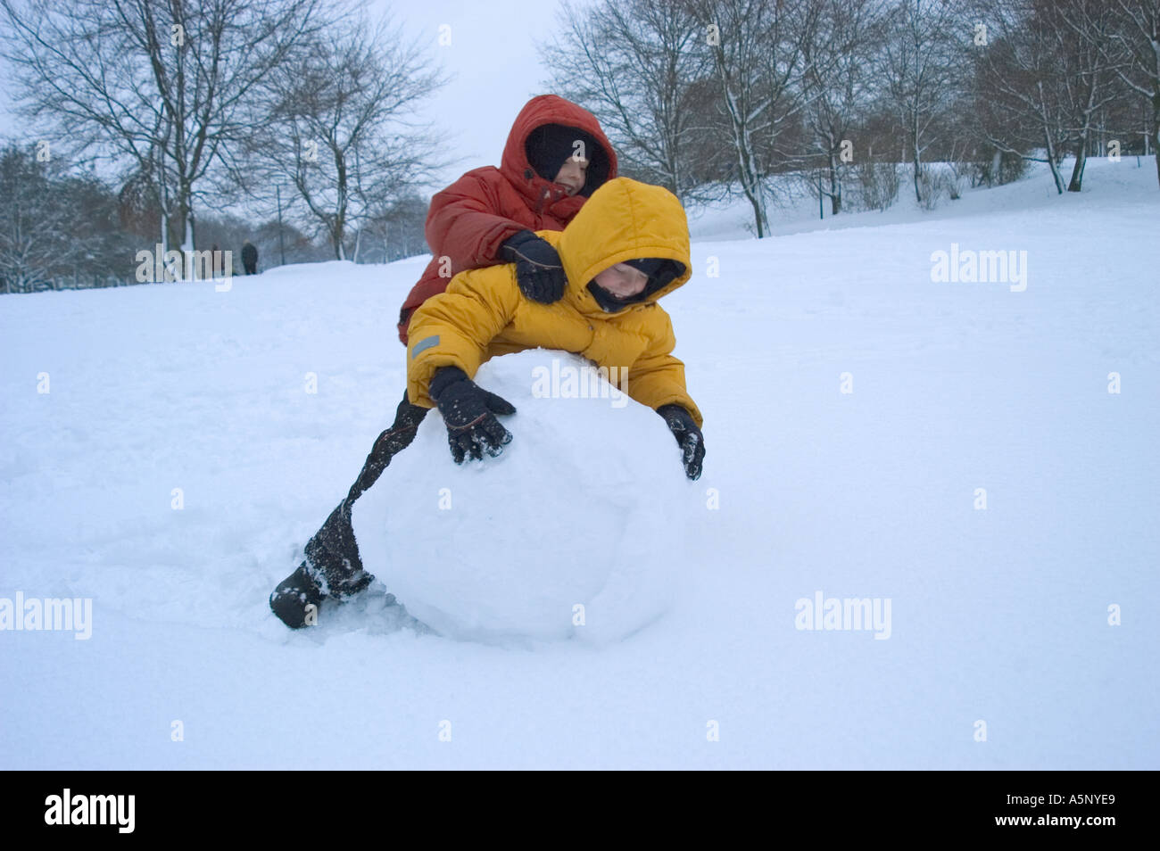 Child rolling snowball hi-res stock photography and images - Alamy
