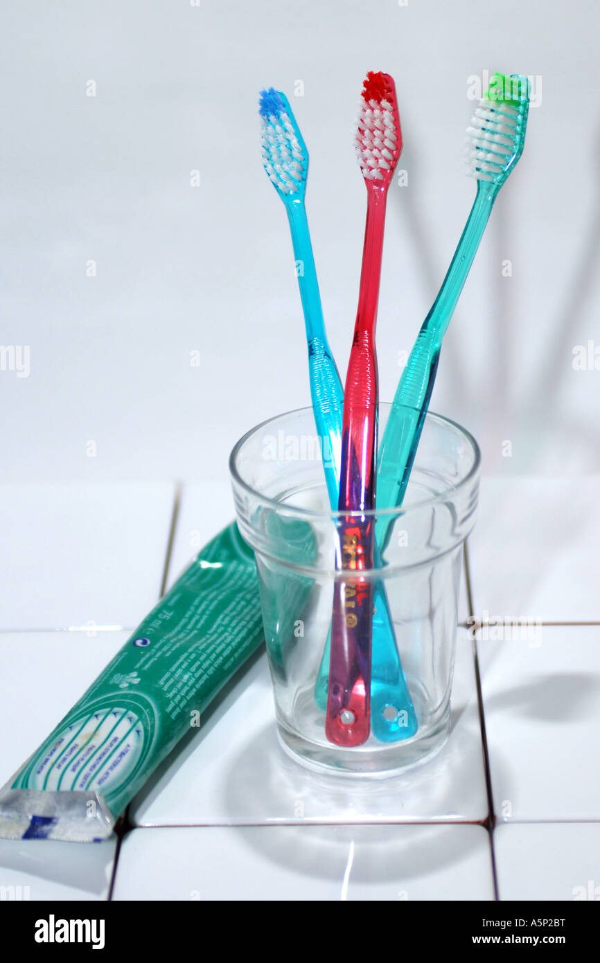 Group of family toothbrushes in a beaker and a tube of toothpaste Stock ...