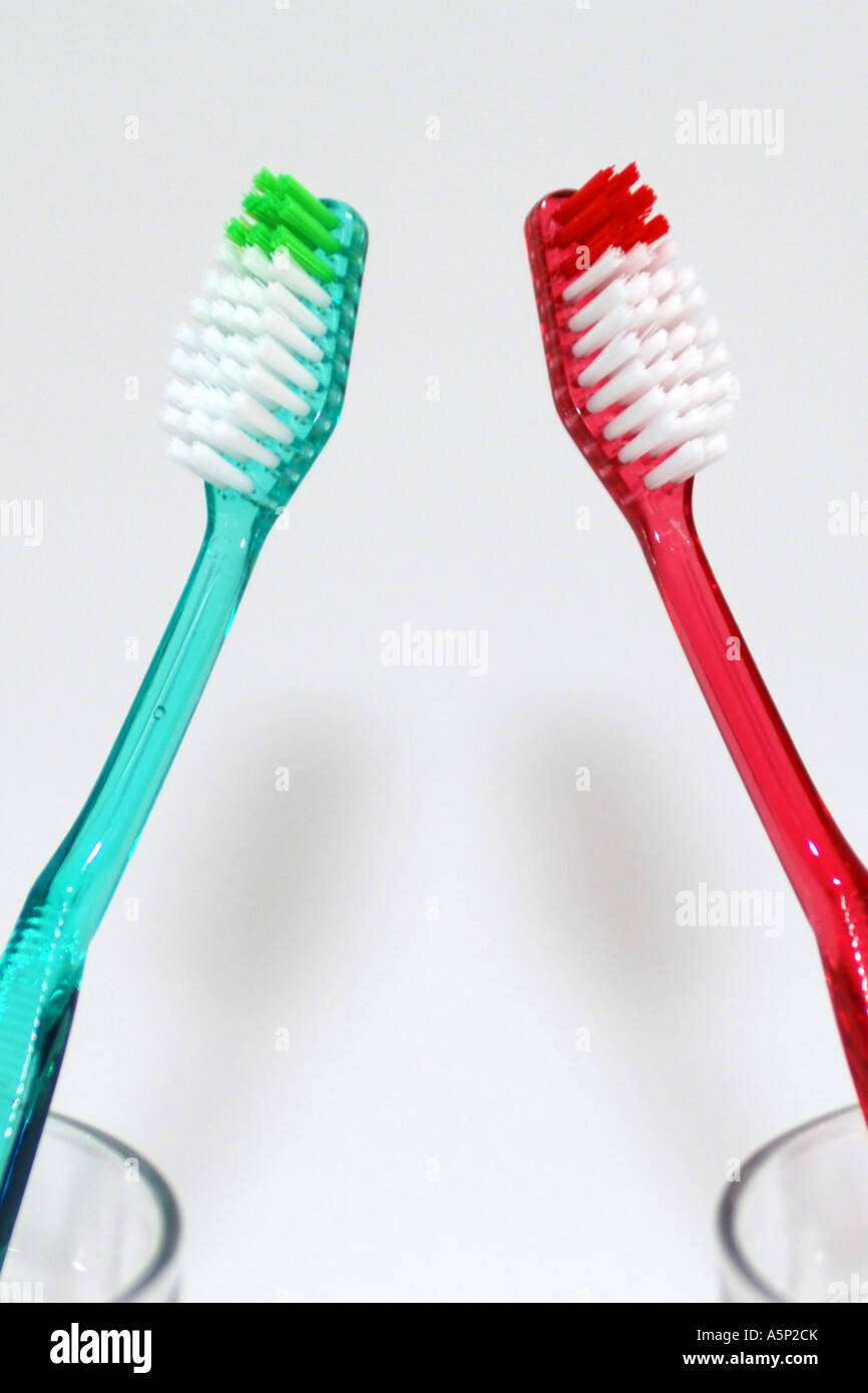 A Green and Red handle toothbrushes in a glass beaker Stock Photo - Alamy
