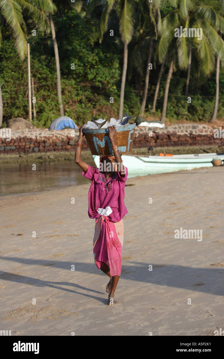 Indian woman collecting fish from local fishing boats on the beach in ...