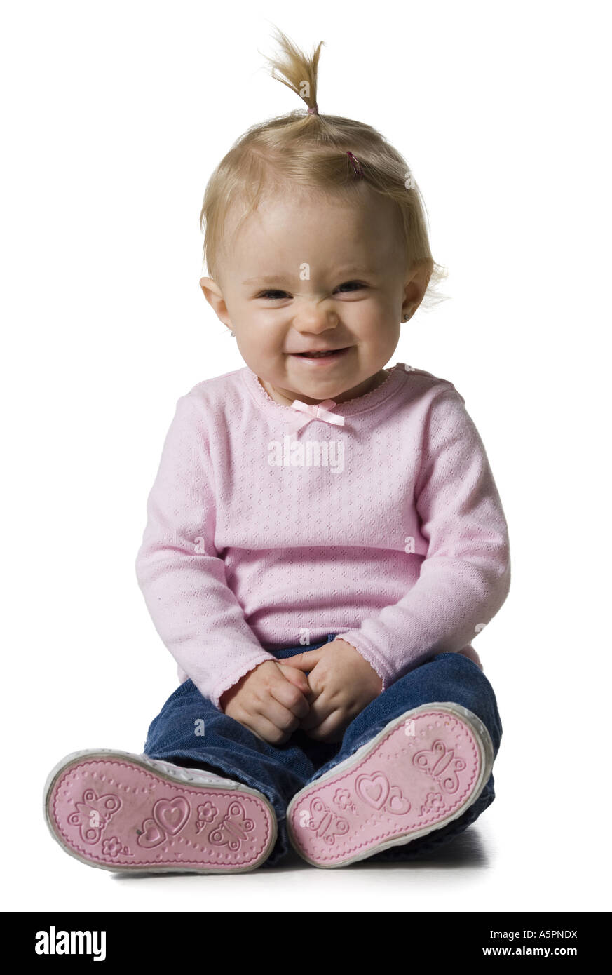 Baby girl with ponytail sitting and smiling Stock Photo Alamy