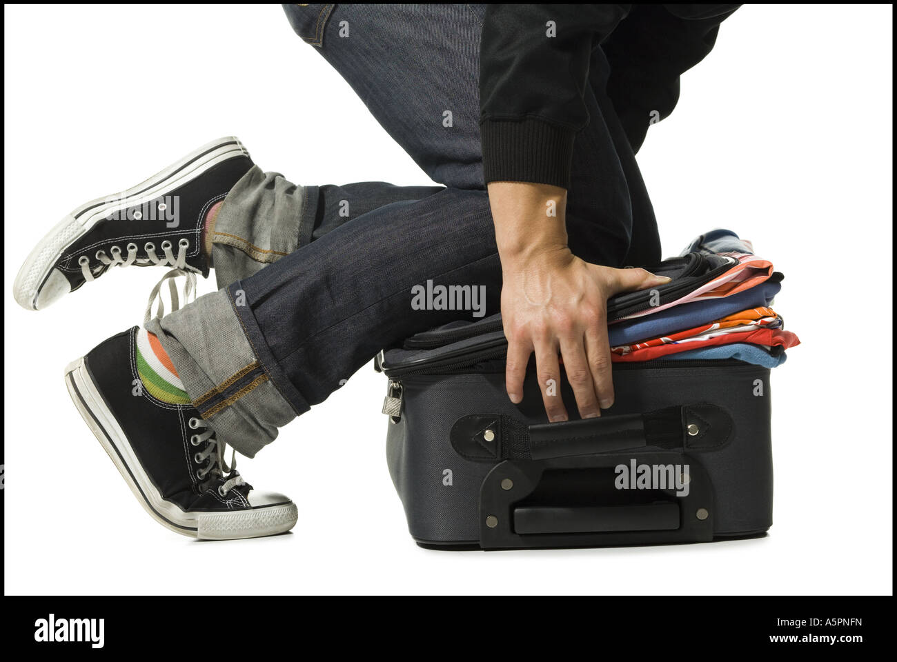 Man forcing clothes into overstuffed suitcase Stock Photo - Alamy