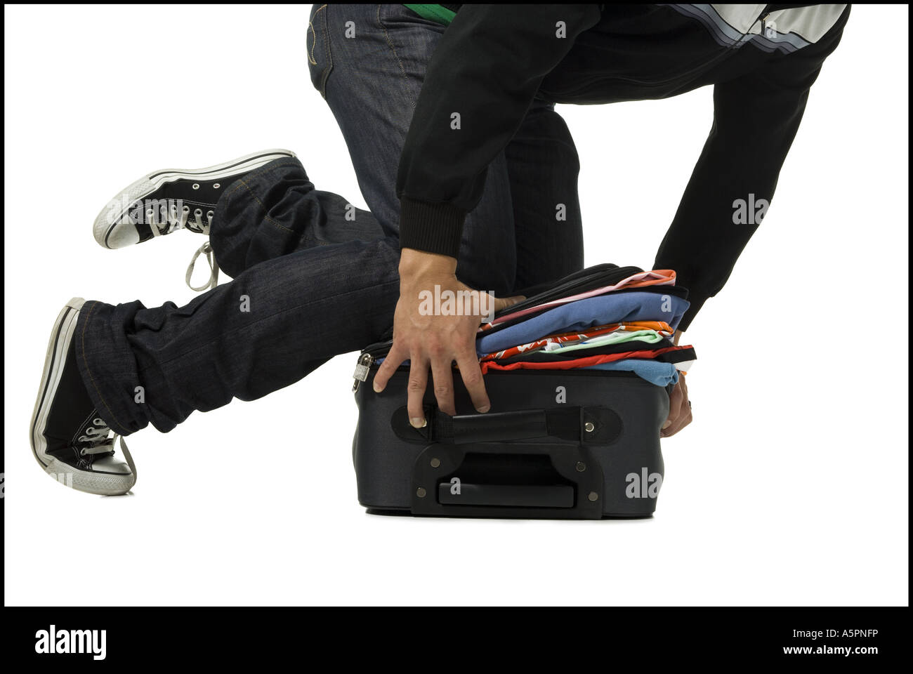 Man forcing clothes into overstuffed suitcase Stock Photo - Alamy