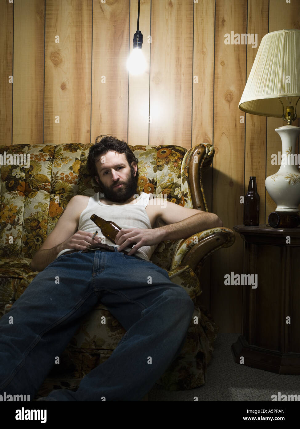Man sitting on sofa with cigarette and beer bottle Stock Photo - Alamy