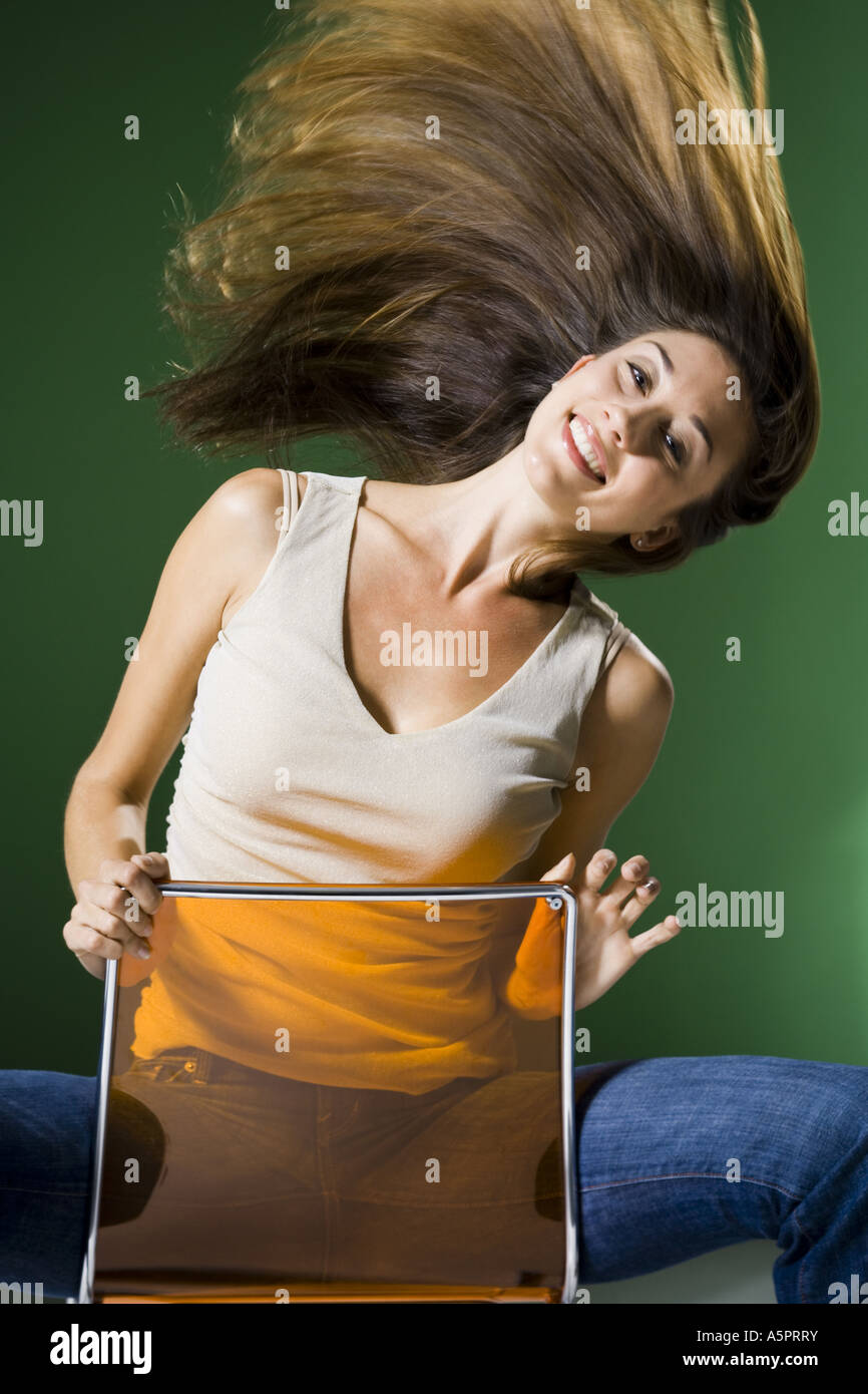 Woman sitting backwards on chair and tossing hair Stock Photo - Alamy