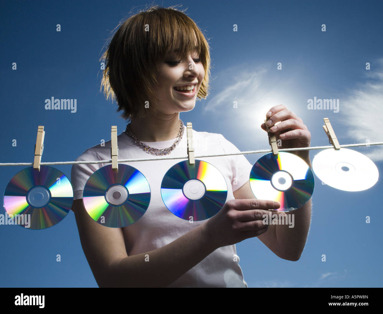 Portrait of a teenage girl drying CDs on a clothesline Stock Photo - Alamy