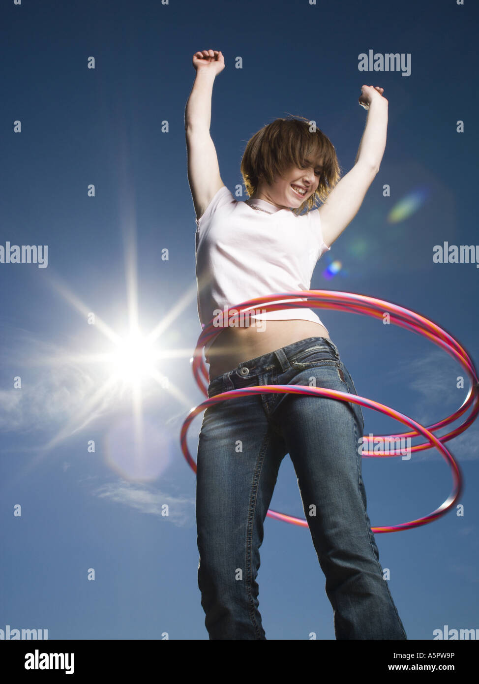 Low angle view of a teenage girl spinning hula hoops around her waist ...