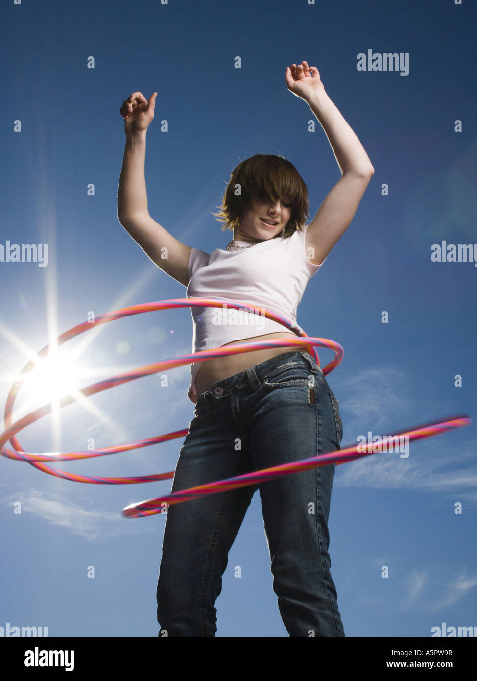 Low angle view of a teenage girl spinning hula hoops around her waist ...