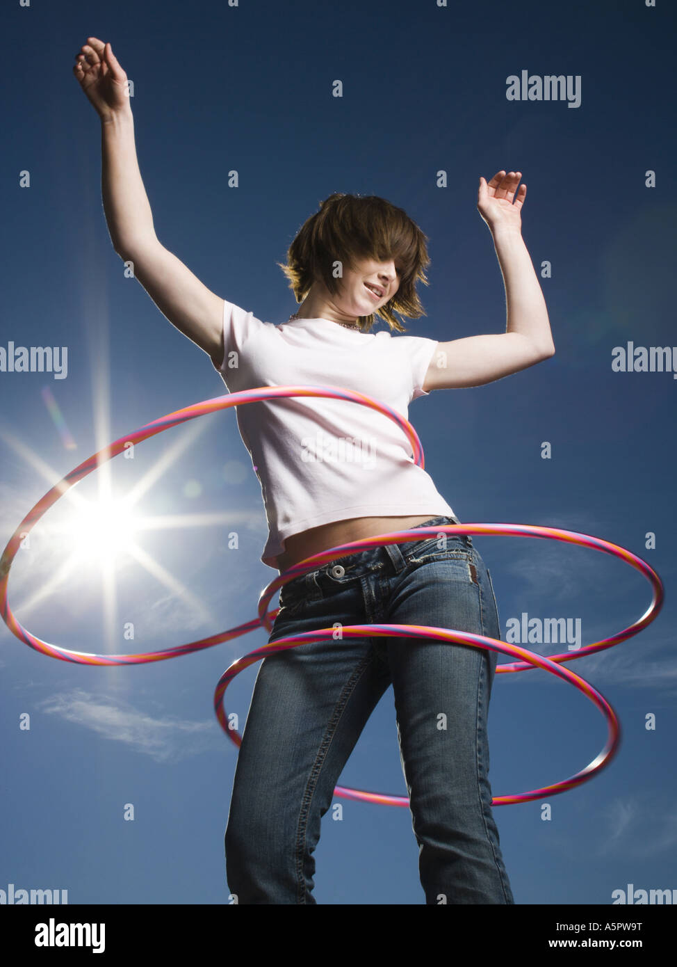 Low angle view of a teenage girl spinning hula hoops around her waist ...