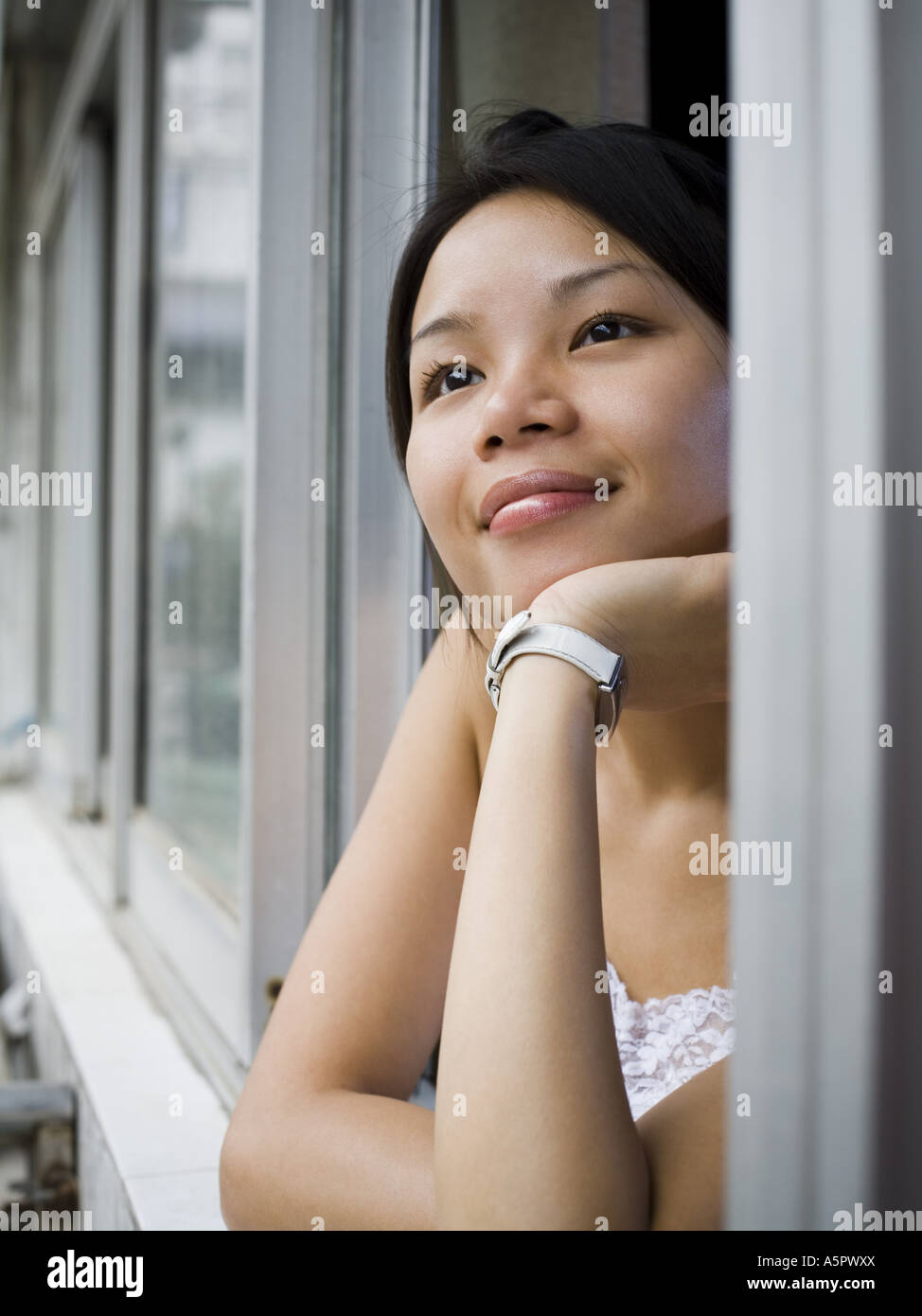 Smiling woman looking out a window Stock Photo - Alamy