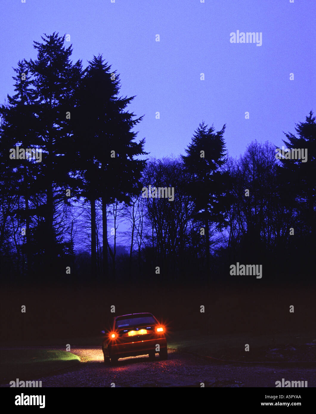 A lone hatchback car makes it s way along a deserted country lane at ...