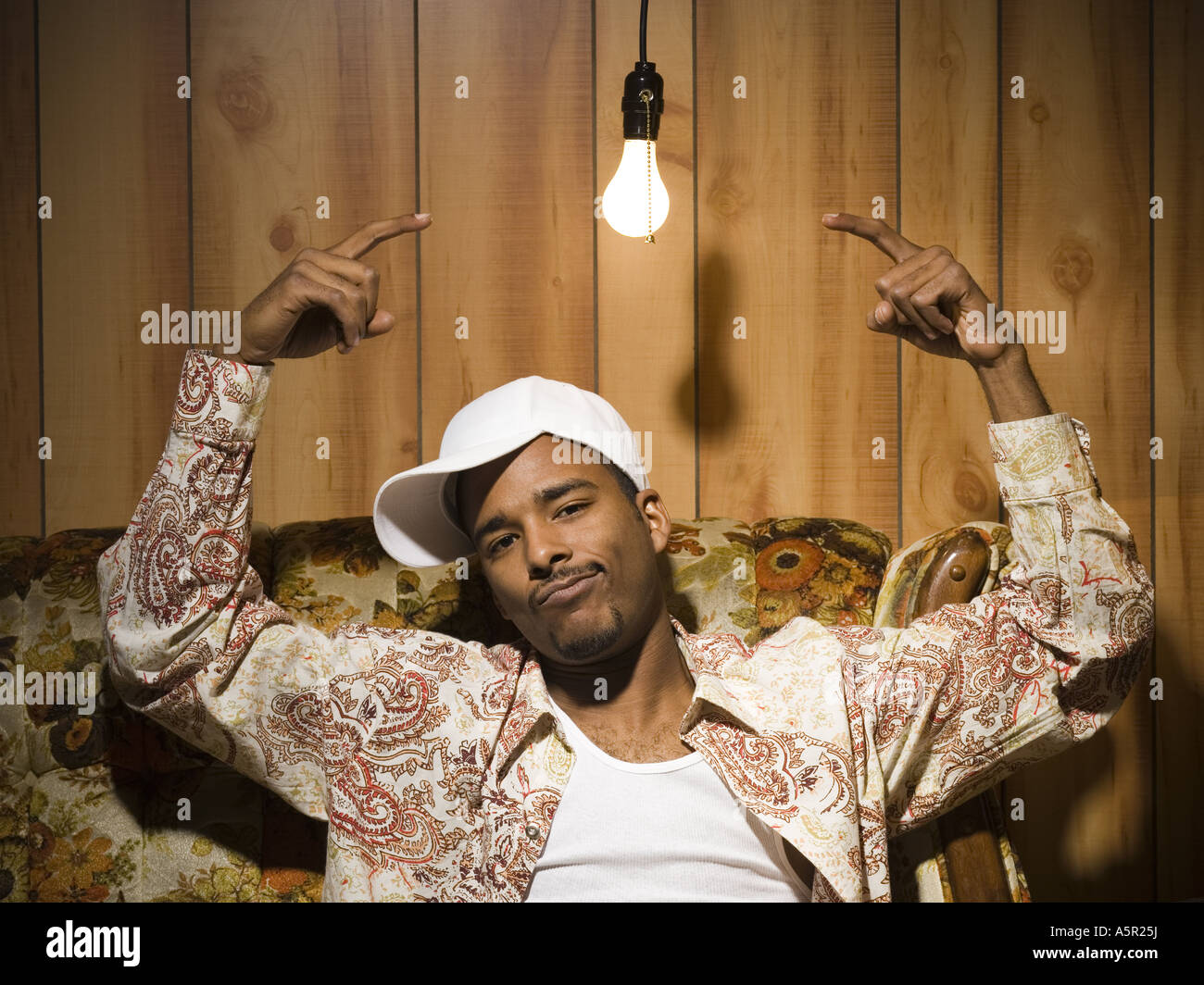 Man sitting on sofa under light bulb pointing up Stock Photo - Alamy