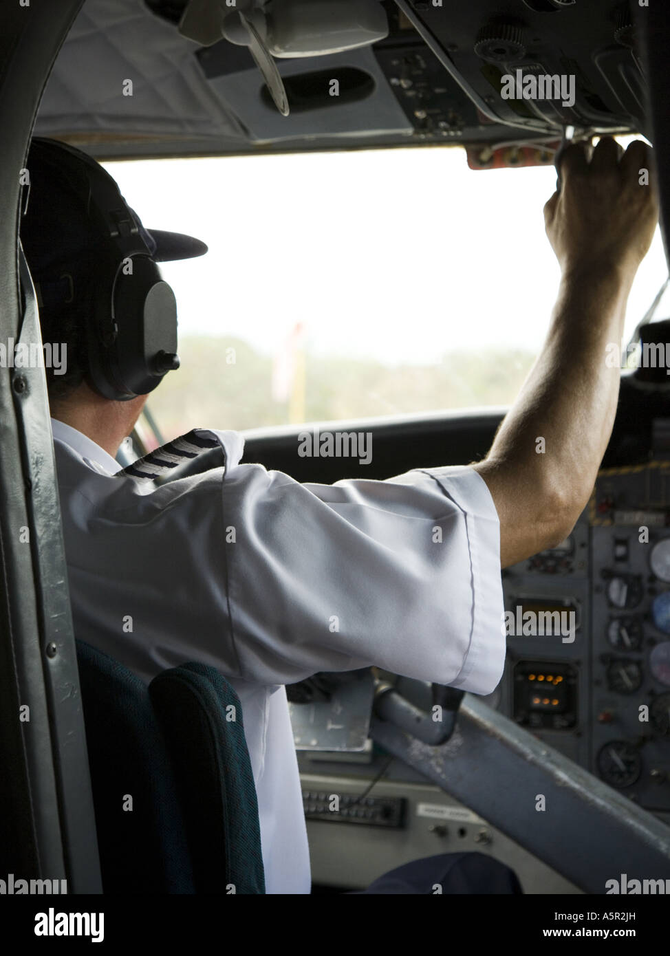 Rear view of a pilot operating the control panel in an airplane Stock ...