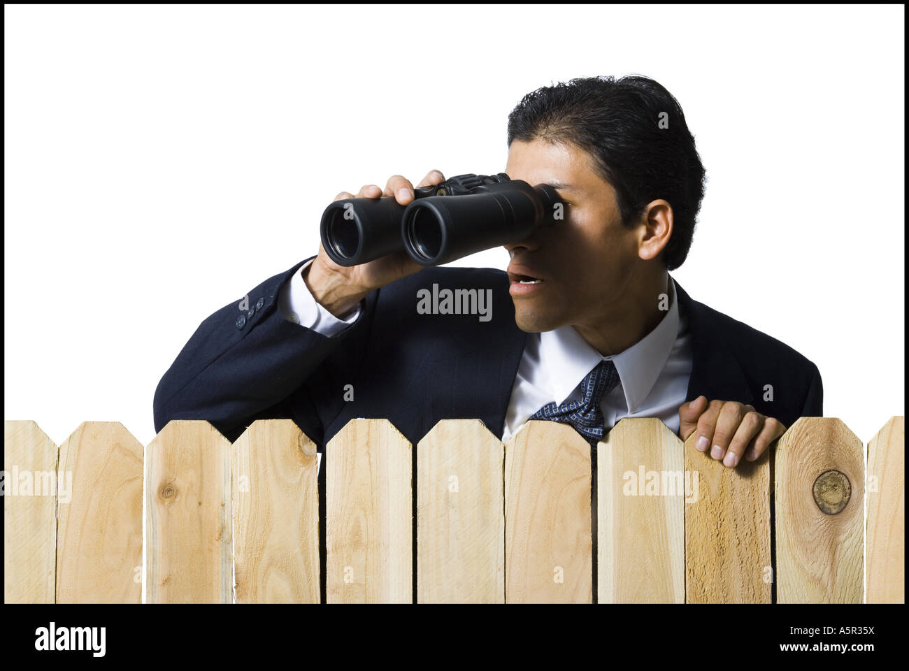 Businessman looking through binoculars over wooden fence Stock Photo ...