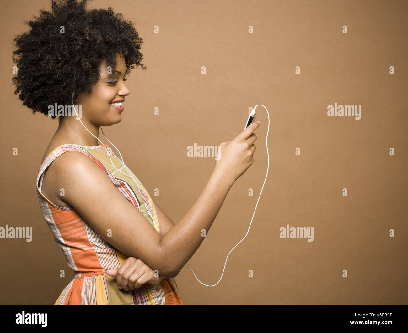 Profile of a young woman listening to an MP3 player Stock Photo - Alamy