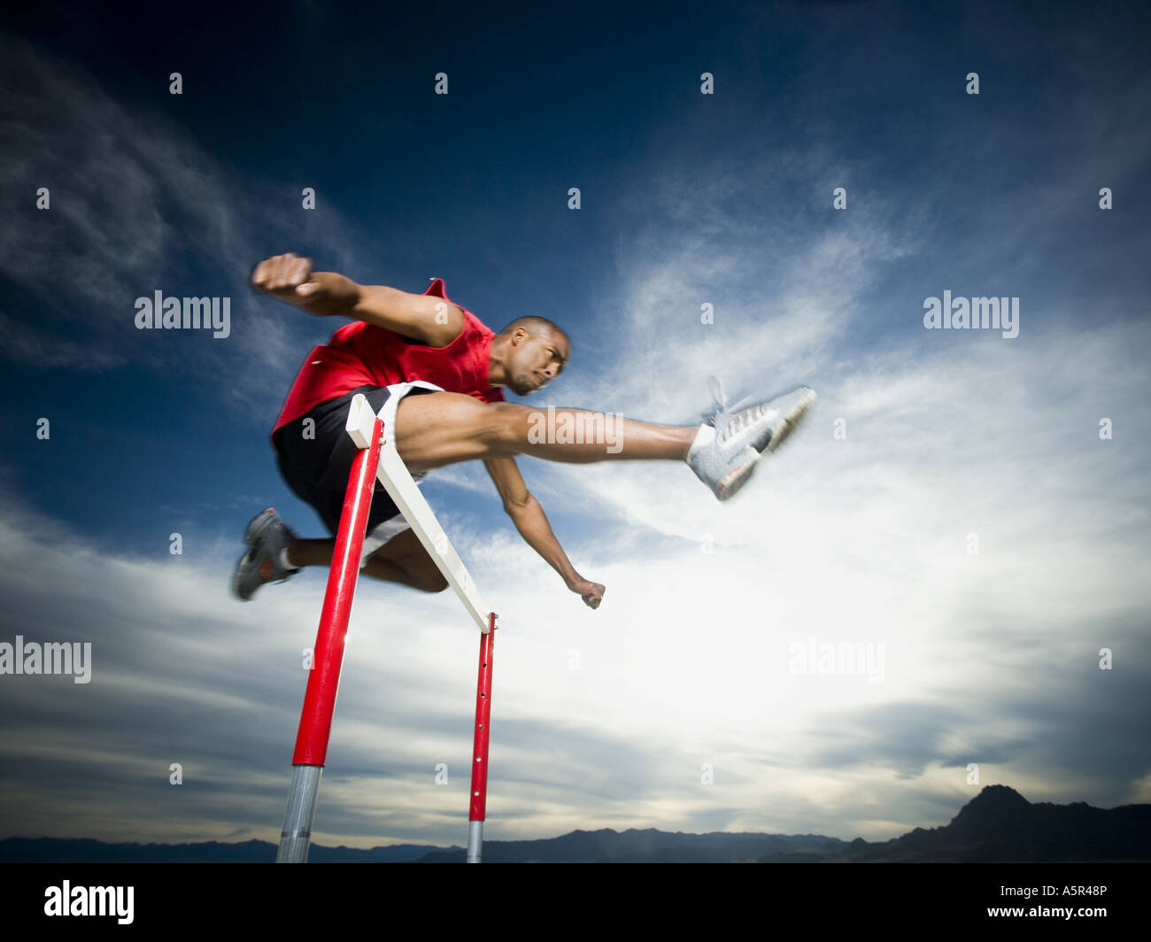 Low angle view of a young man jumping over a hurdle in a race Stock ...