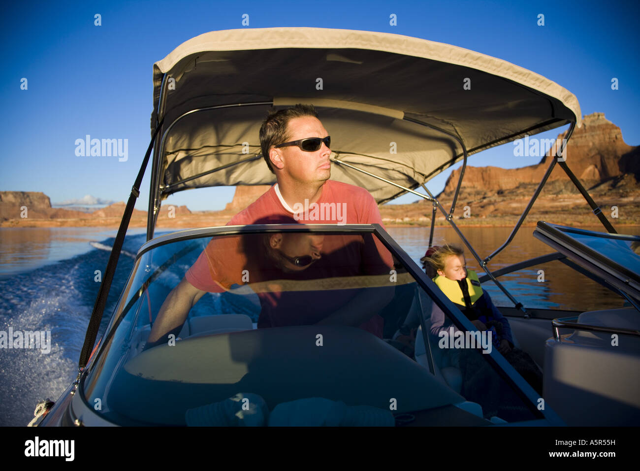Man driving boat with young girl Stock Photo - Alamy