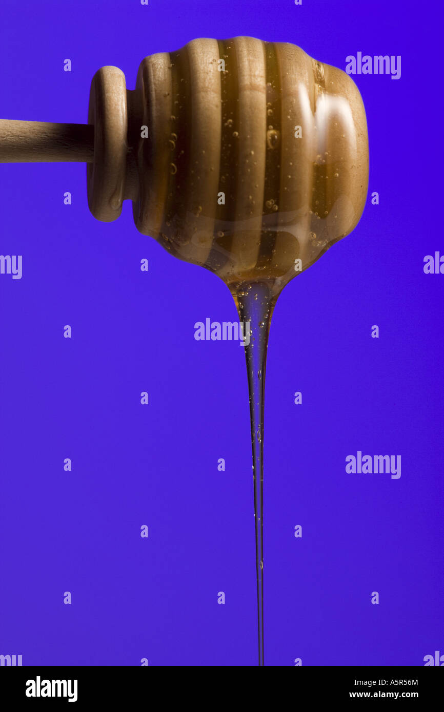 Drop of honey falling from a honey dipper Stock Photo - Alamy