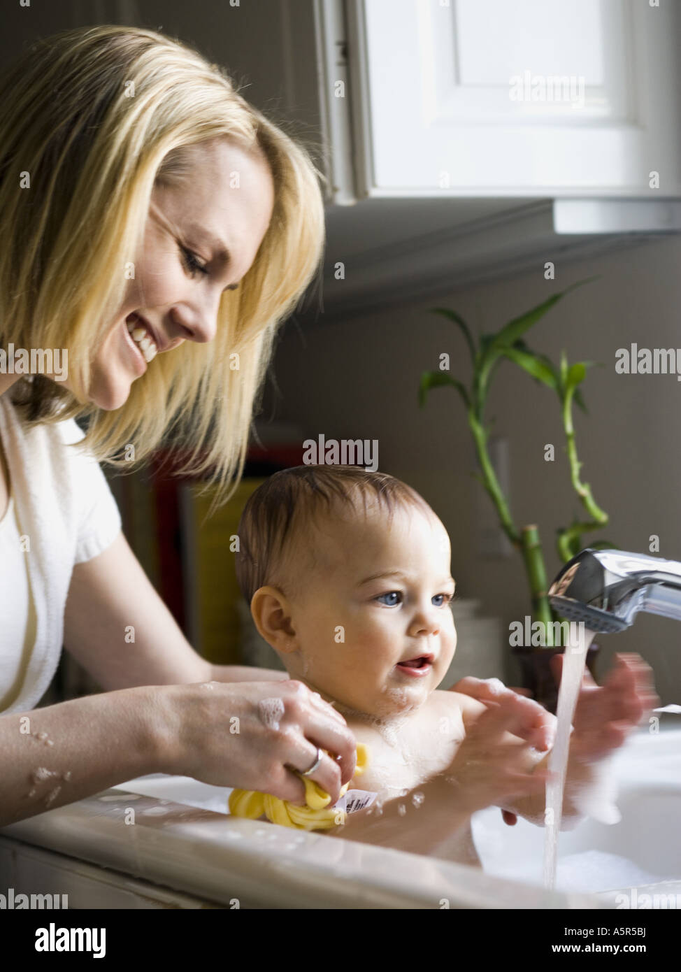 Woman bathing baby in sink Stock Photo - Alamy