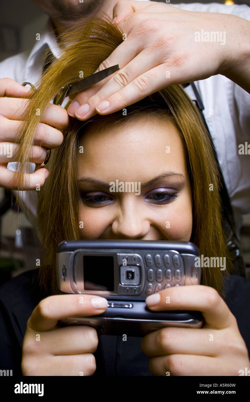 Young woman with camera phone having hair cut smiling Stock Photo - Alamy