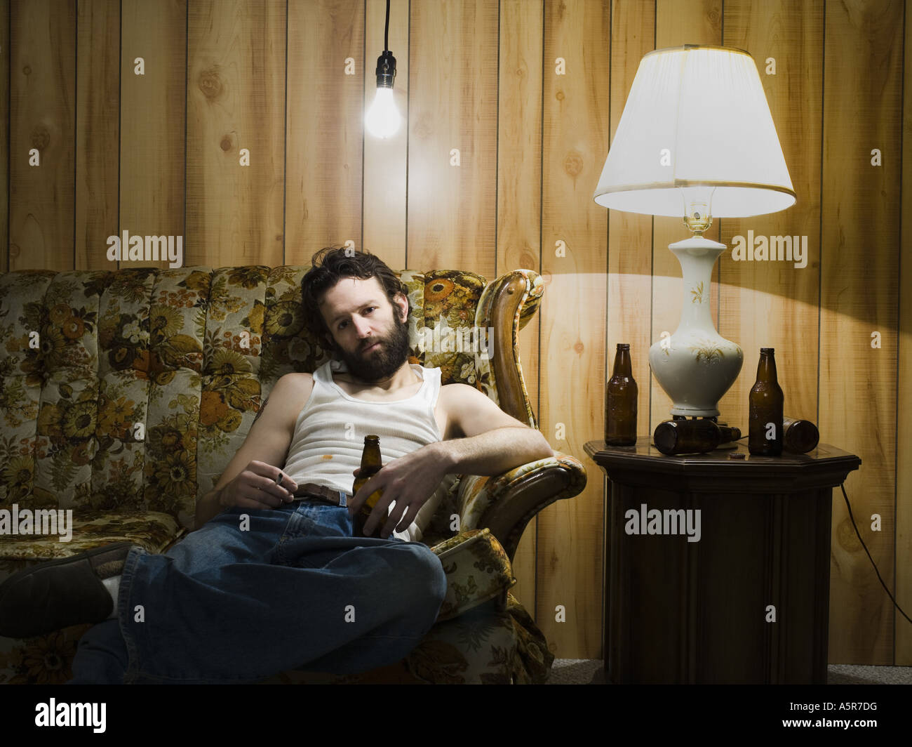 Man on couch with beer bottle and cigarette Stock Photo - Alamy