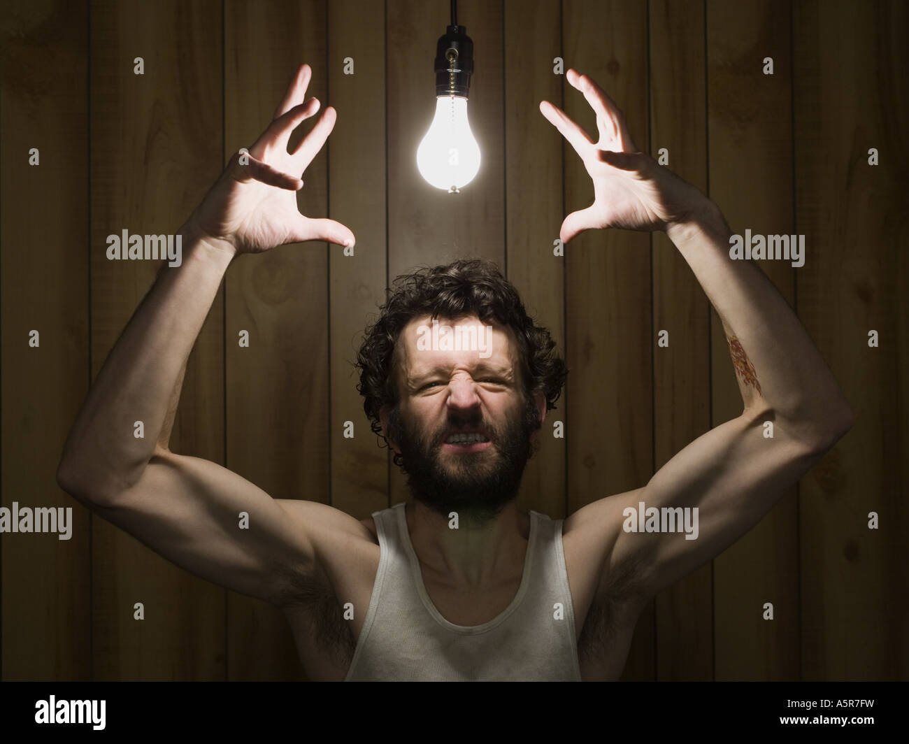 Man reaching to light bulb gritting teeth Stock Photo - Alamy