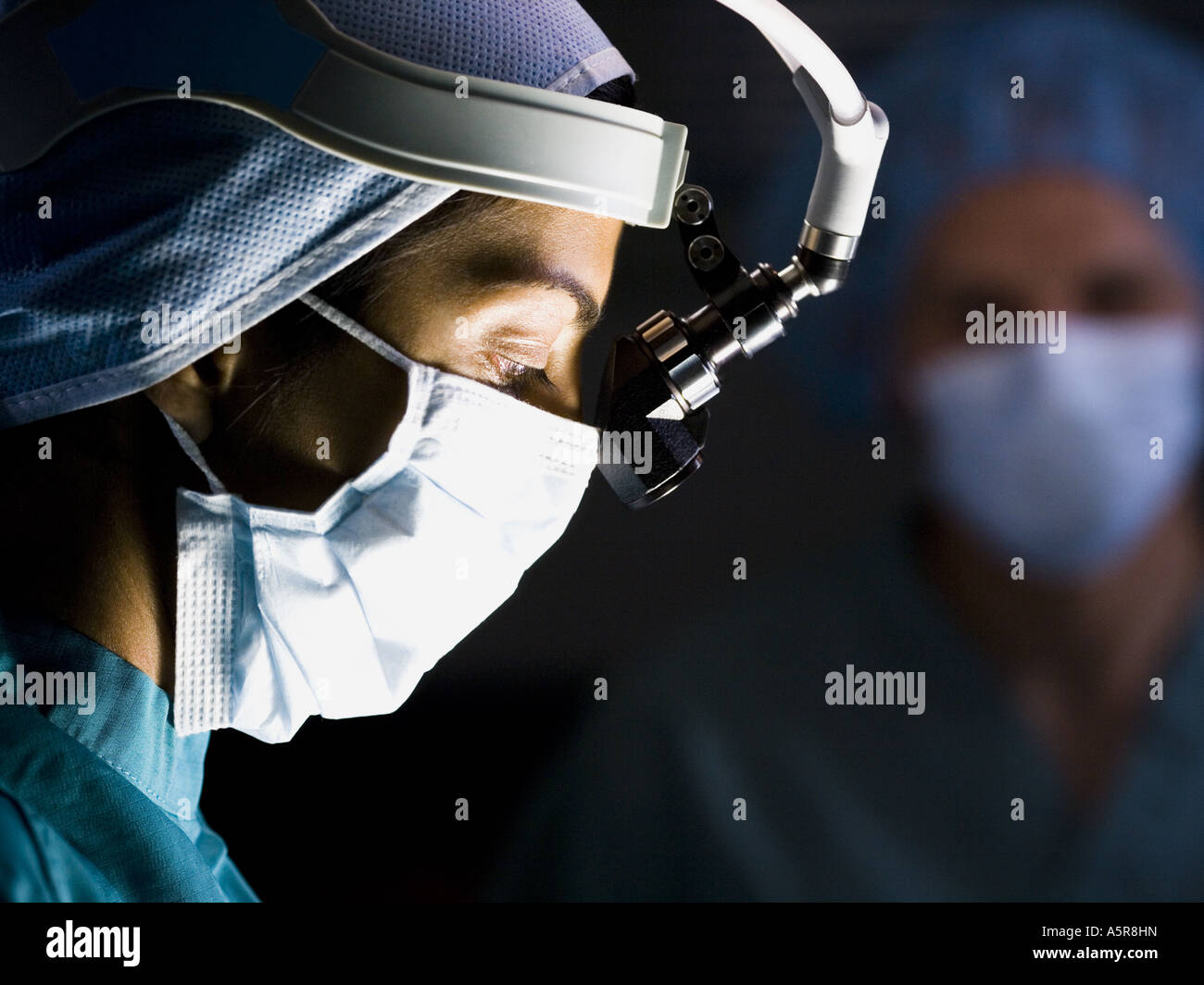 Female doctor in scrubs with head light in surgery Stock Photo - Alamy