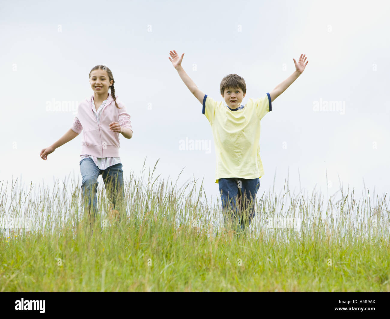 Boy and a girl running in a field Stock Photo - Alamy