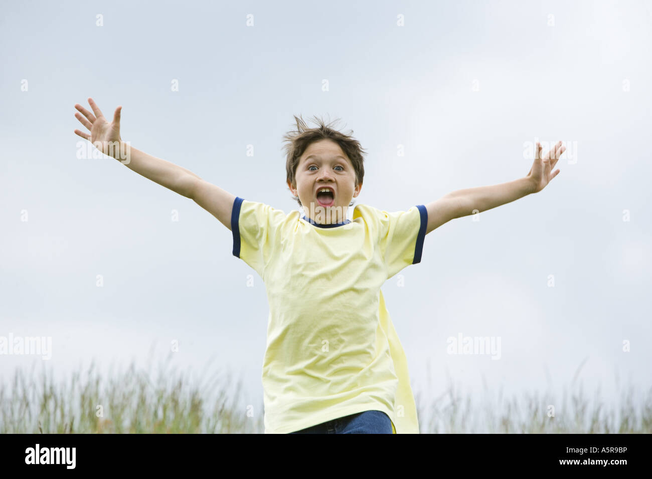 Portrait of a boy running with his arms outstretched Stock Photo - Alamy