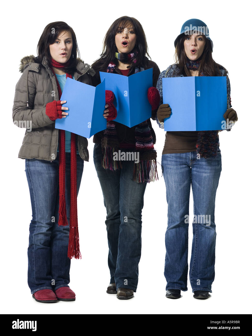 Three women singing with winter coats and sheet music Stock Photo - Alamy