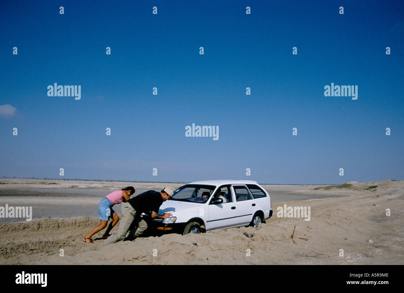 PASSENGERS PUSHING CAR STUCK IN SAND WHILE CROSSING THE BAYOVAR DESERT ...
