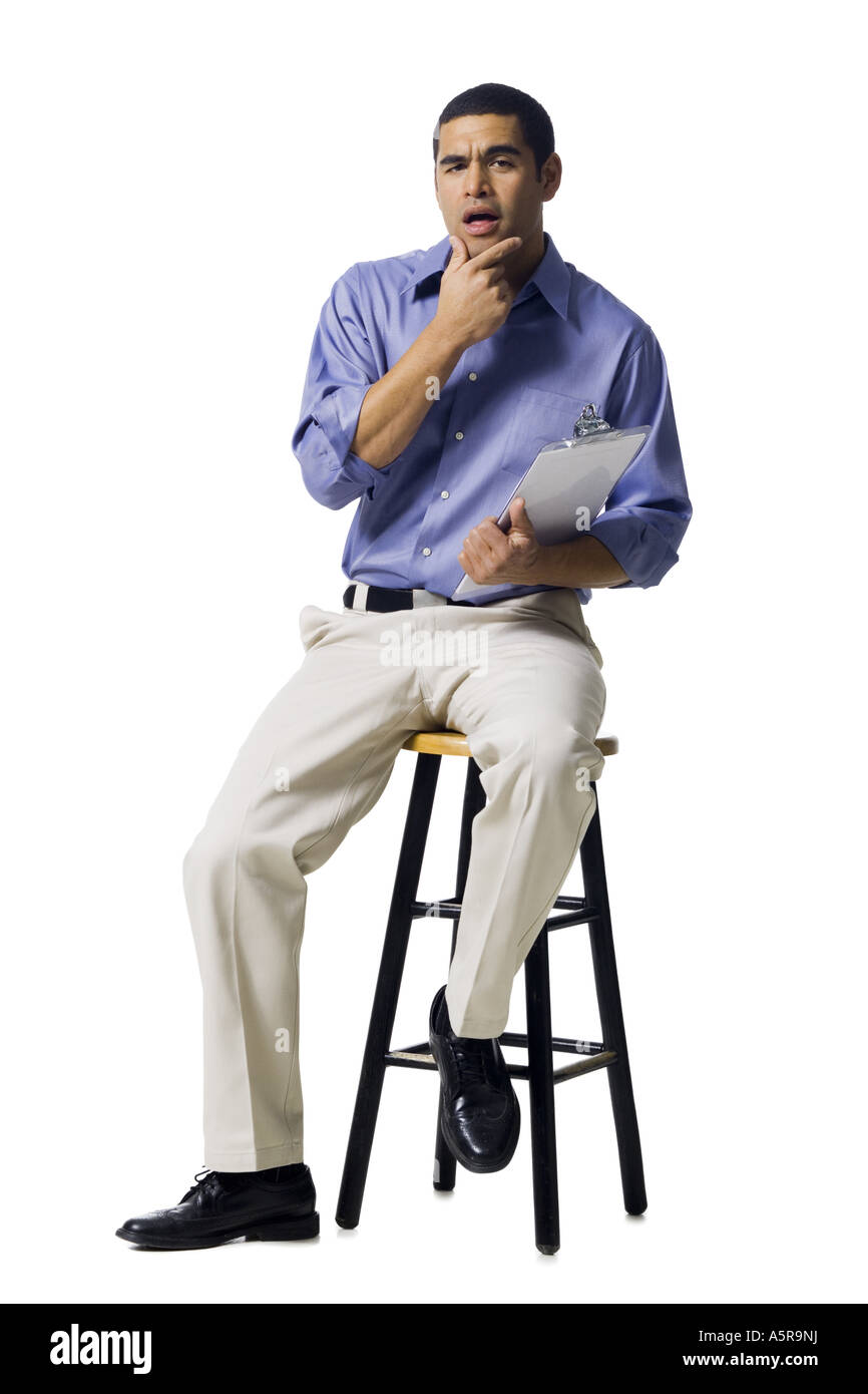 Man sitting on stool with clipboard gesturing Stock Photo - Alamy