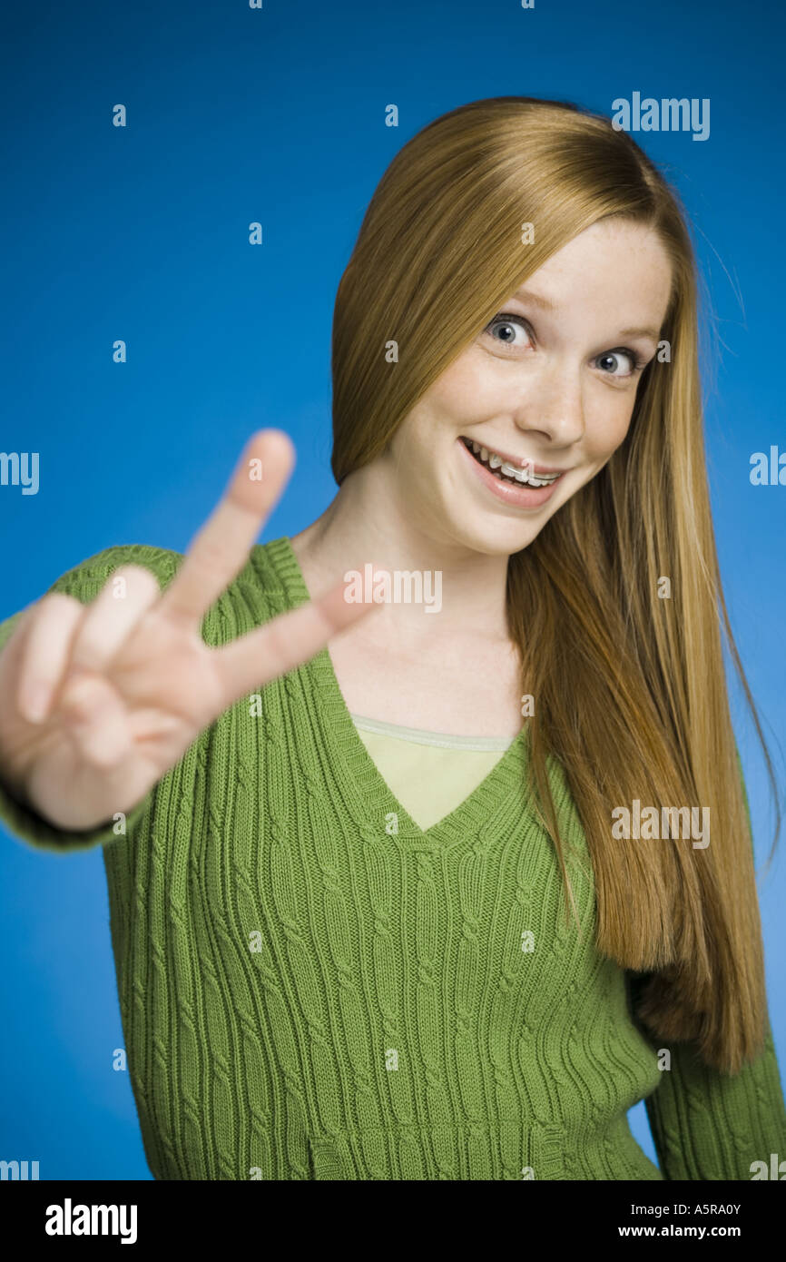 Girl making peace sign smiling Stock Photo - Alamy