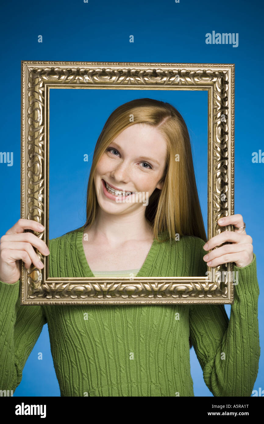 Girl looking through picture frame smiling Stock Photo - Alamy