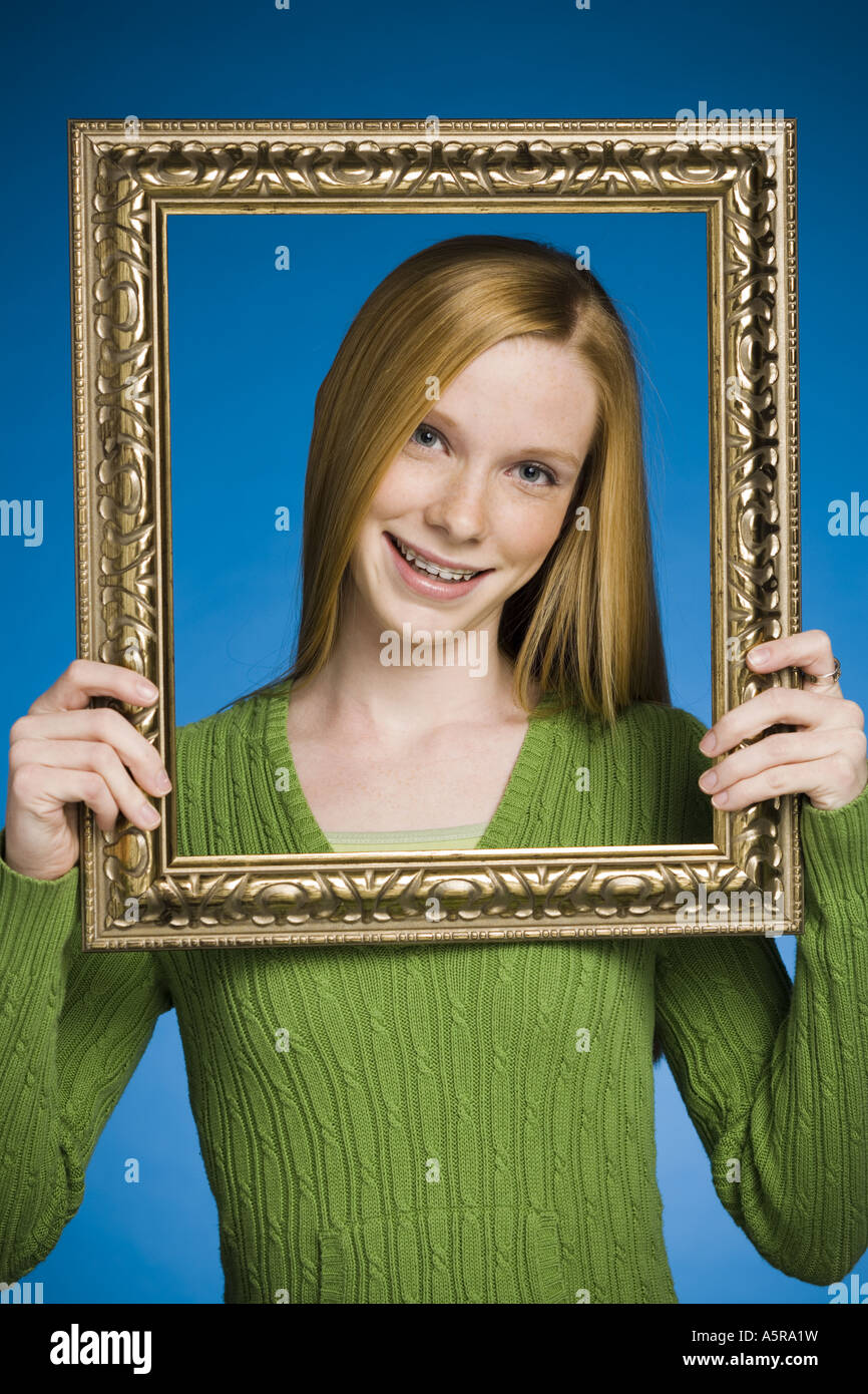 Girl looking through picture frame smiling Stock Photo - Alamy