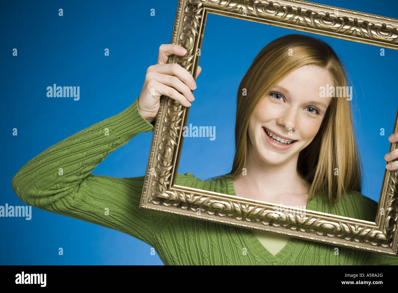 Girl looking through picture frame smiling Stock Photo - Alamy