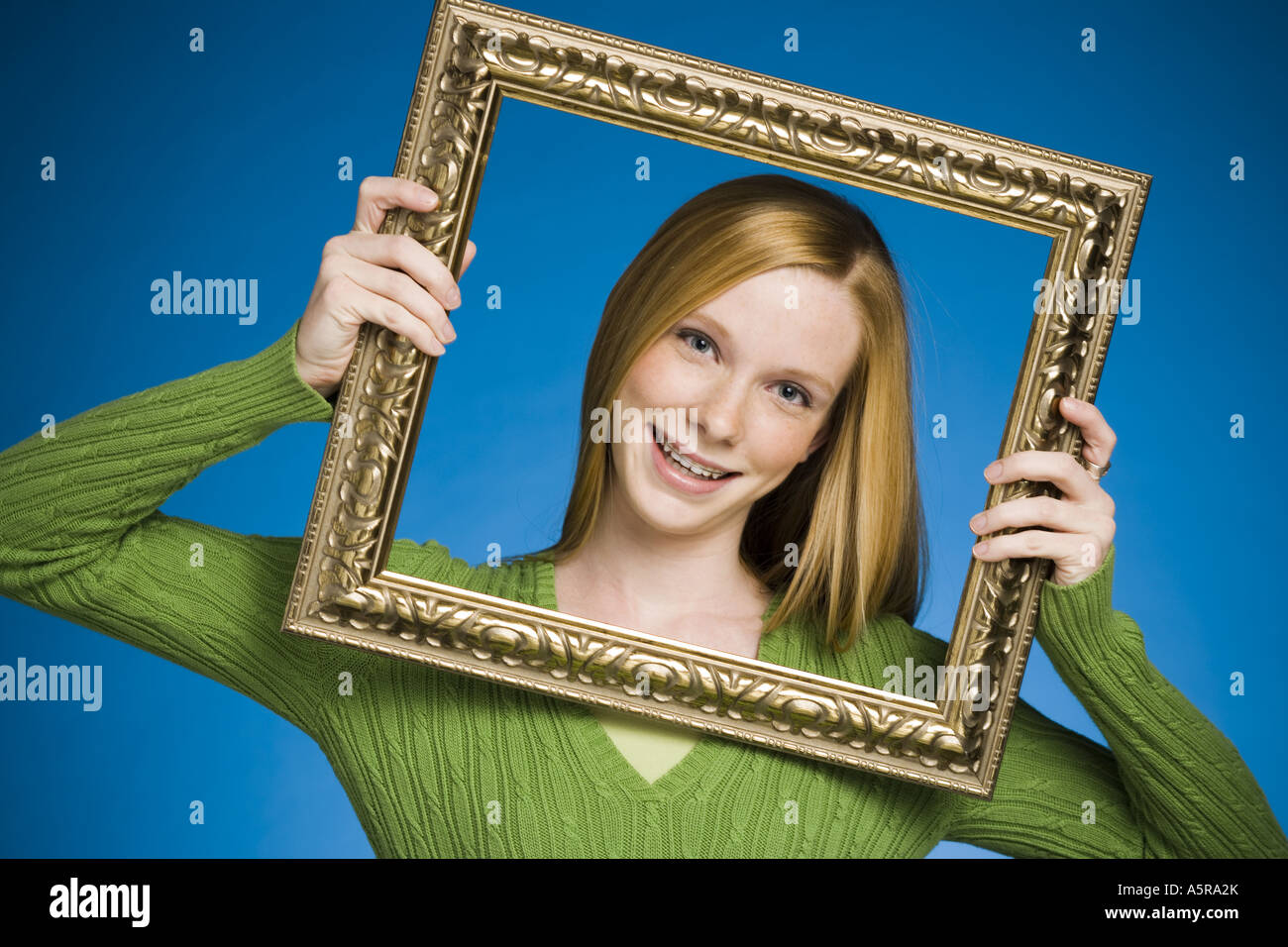 Girl looking through picture frame smiling Stock Photo - Alamy